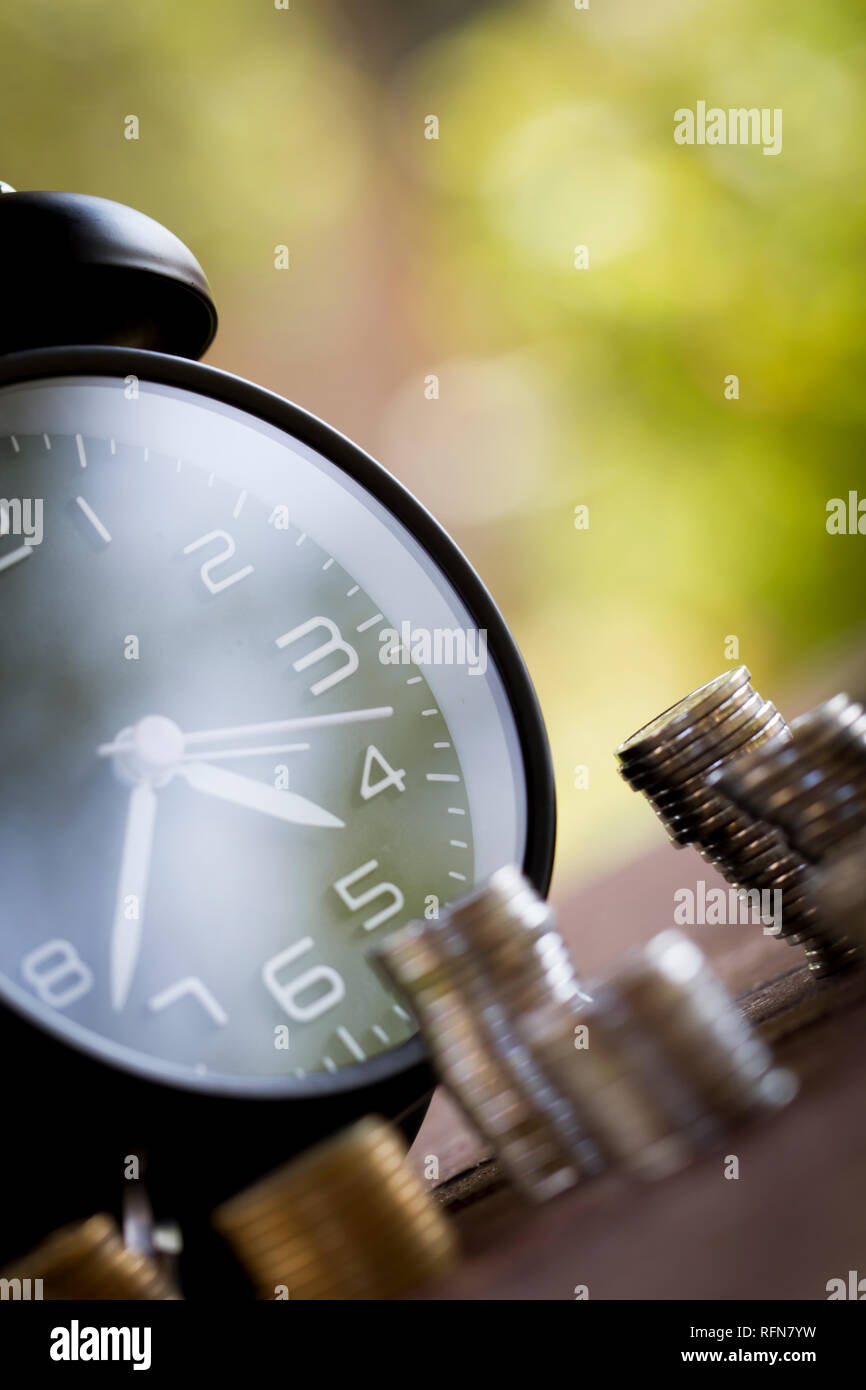 Black alarm clock with money Stock Photo - Alamy