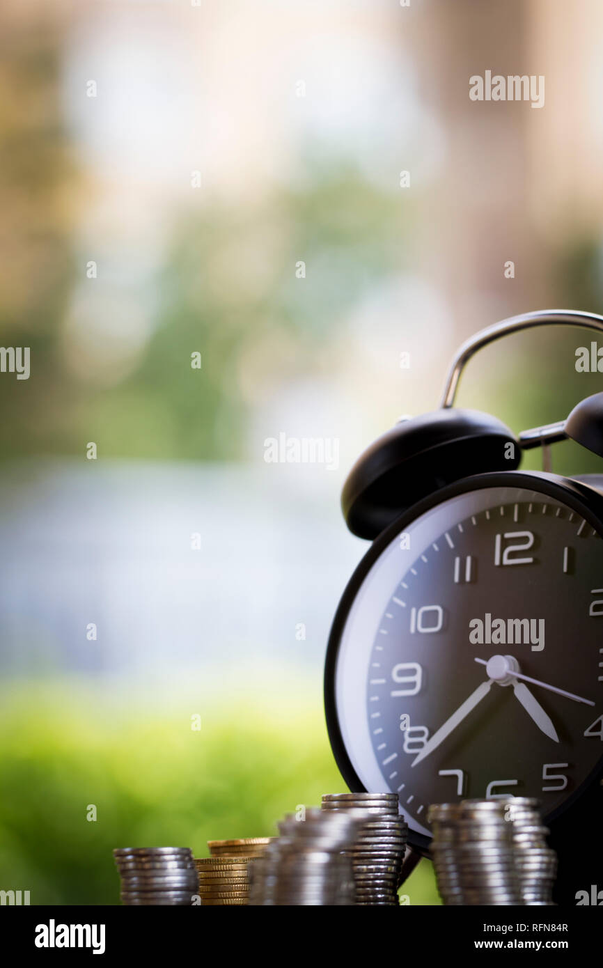 Black alarm clock with money Stock Photo - Alamy