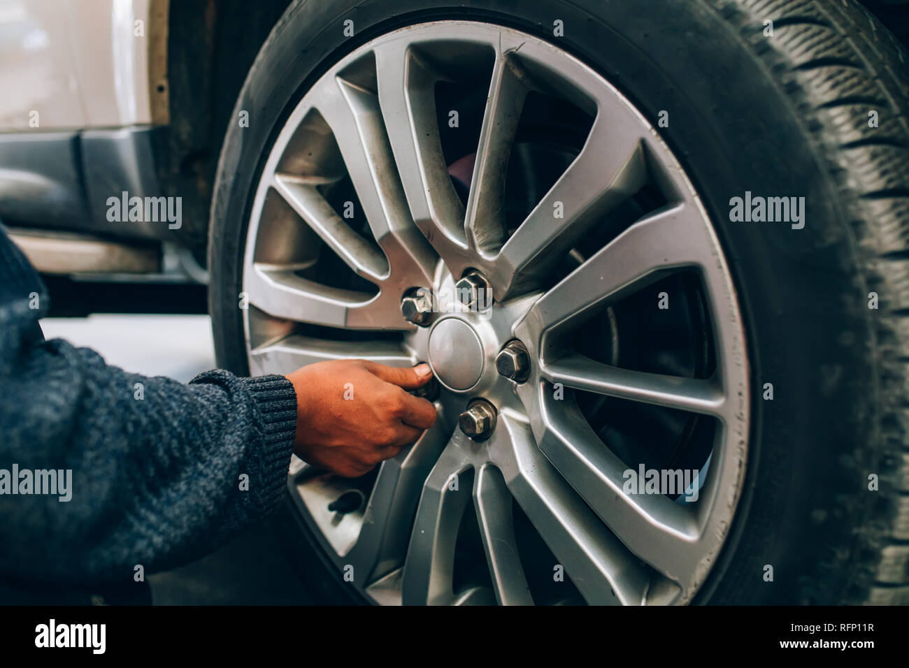 Mechanician changing car wheel in auto repair shop. Mechanic adjusting ...