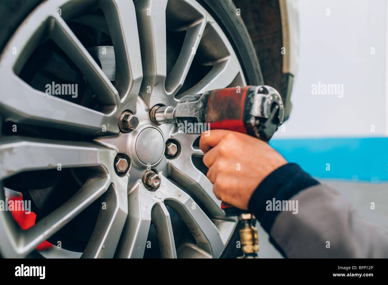 Mechanician changing car wheel in auto repair shop. Mechanic adjusting ...