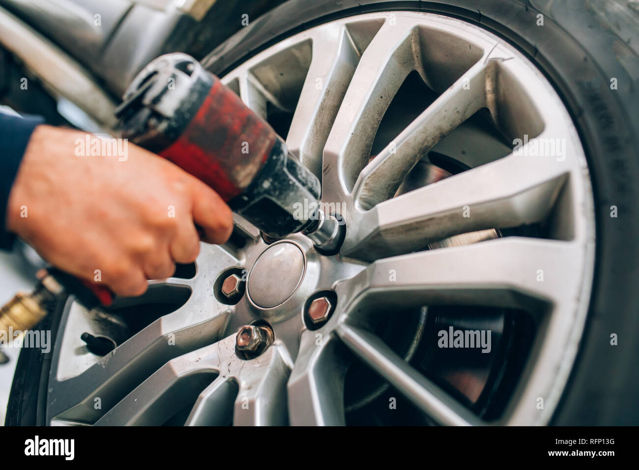 Mechanician changing car wheel in auto repair shop. Mechanic adjusting ...