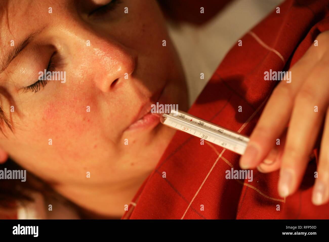Woman measures her blood heat with a clinical thermometer, common cold ...
