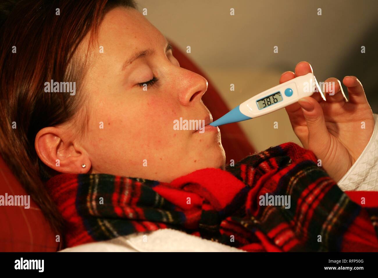 Woman measures her blood heat with a clinical thermometer, common cold ...
