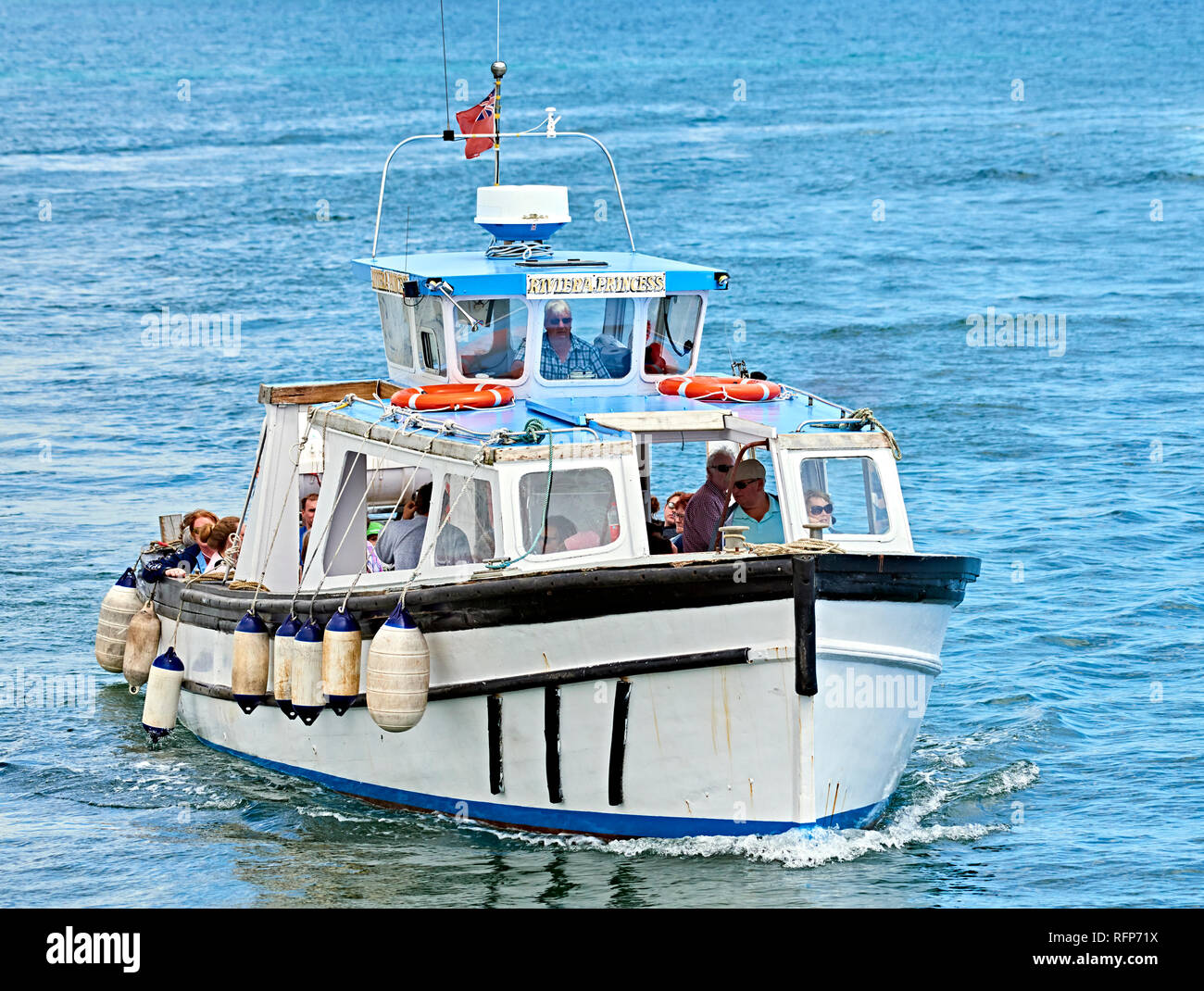 A small semi-enclosed passenger ferry slowly approaches the quayside ...