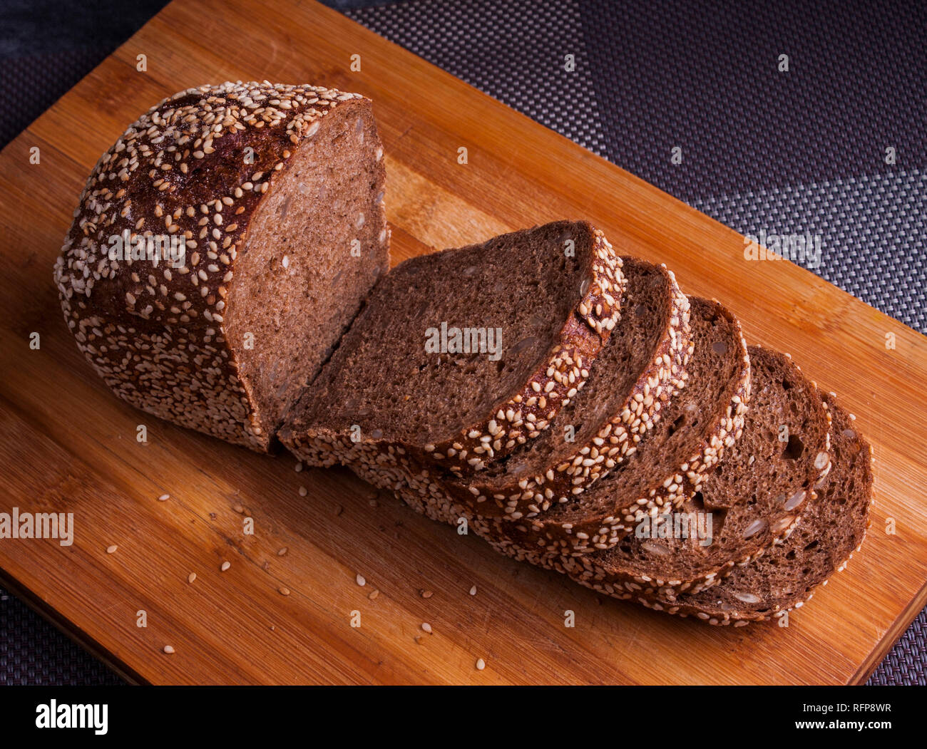 Black multigrain bread sliced on a bamboo board with sesame and ...