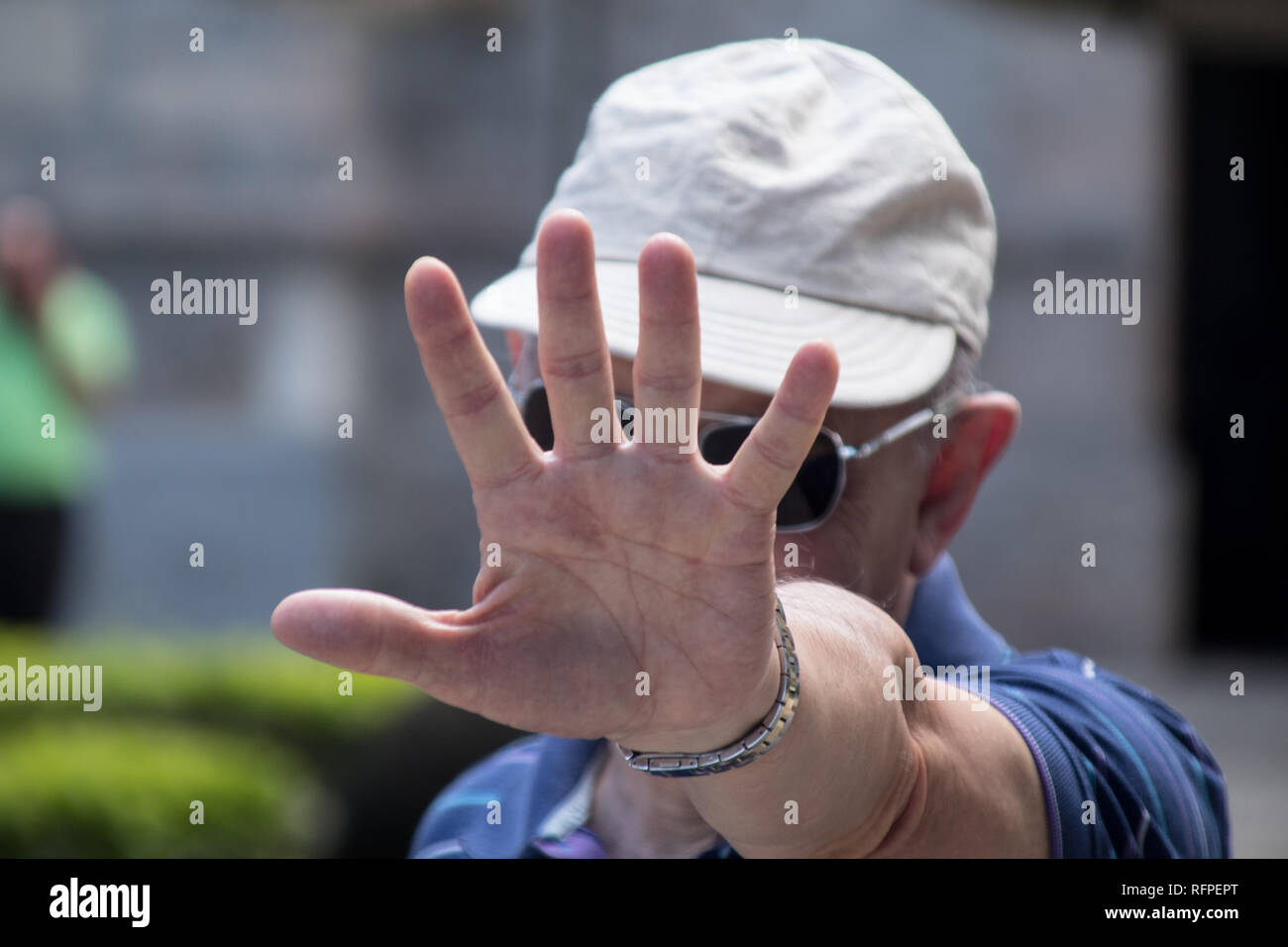 A portrait of a man that is playfully hiding his face from the camera ...