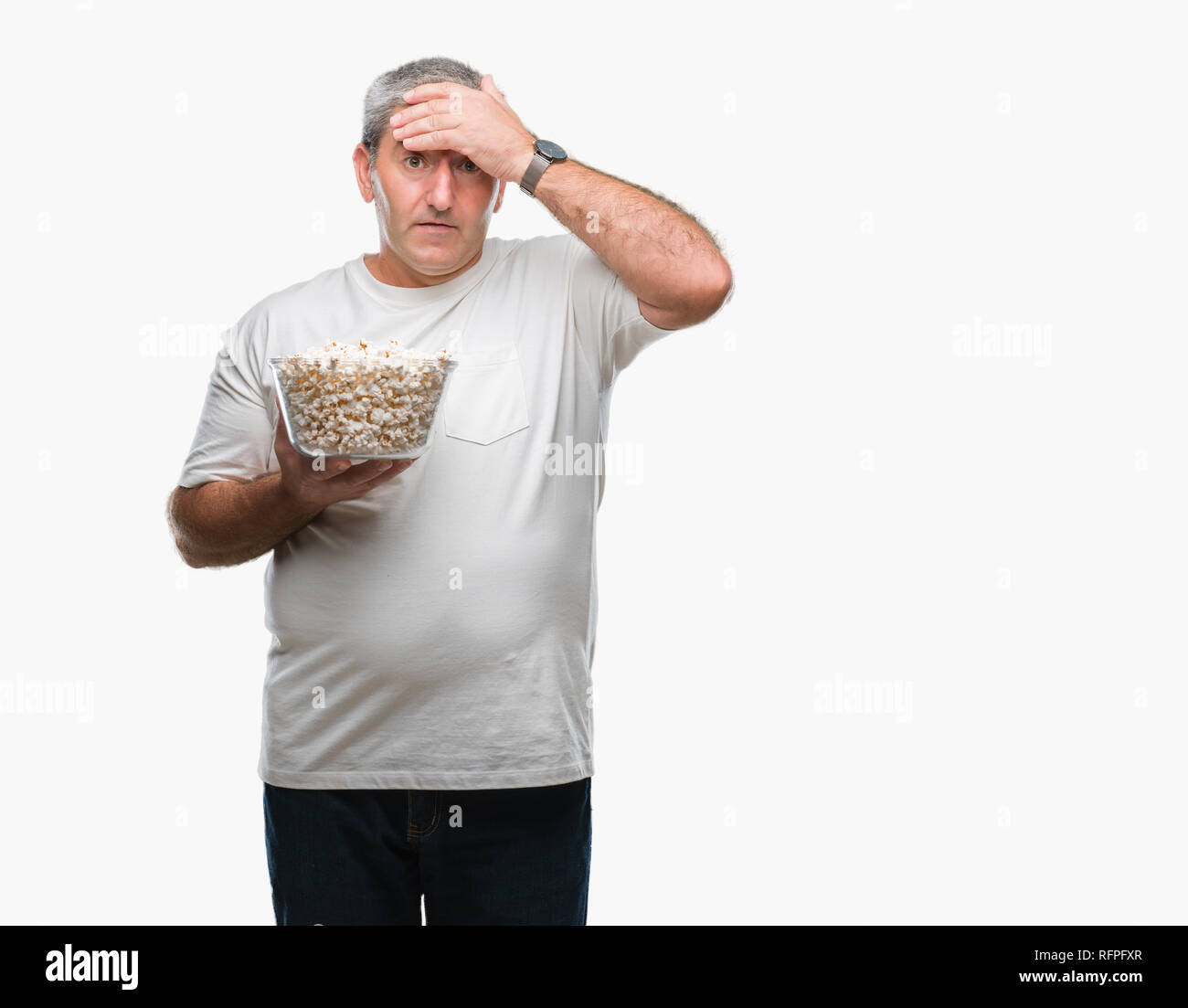 Handsome senior man eating popcorn over isolated background stressed ...
