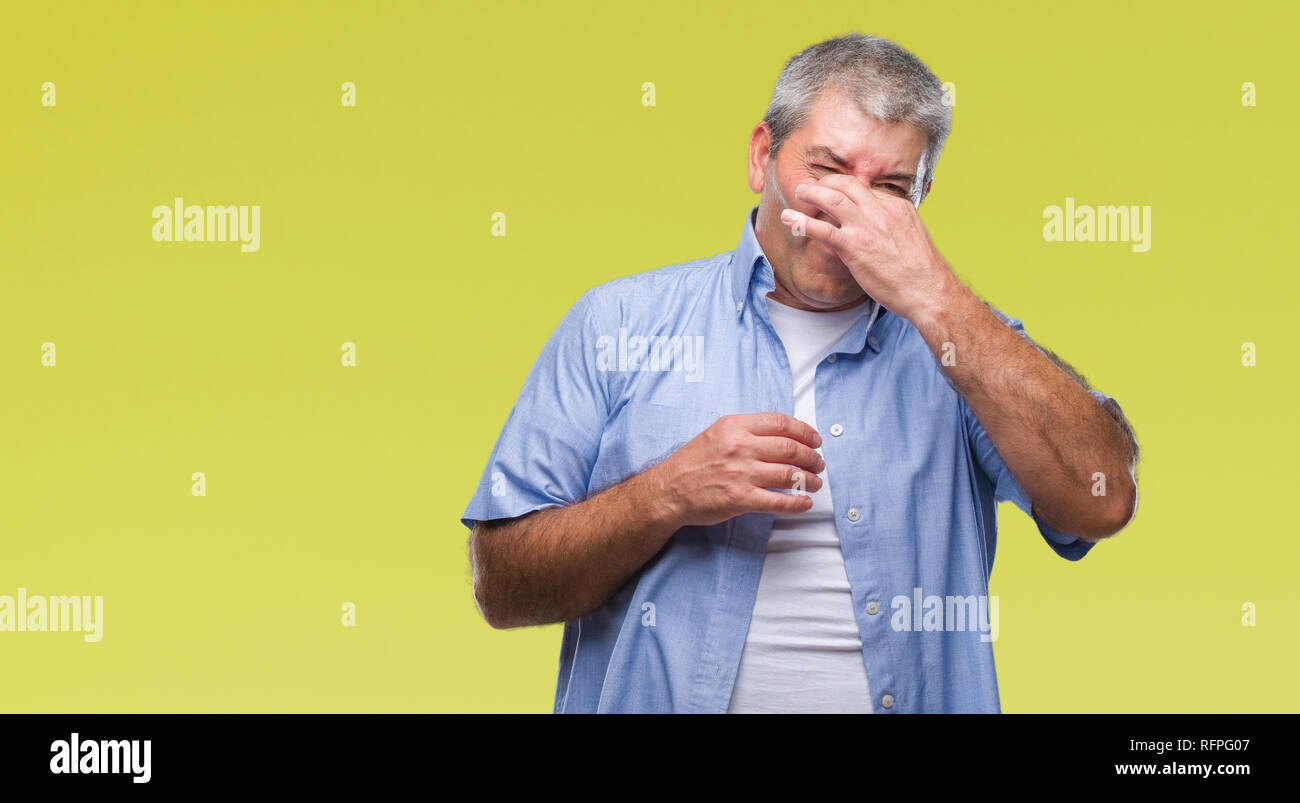 Handsome senior man over isolated background smelling something stinky ...