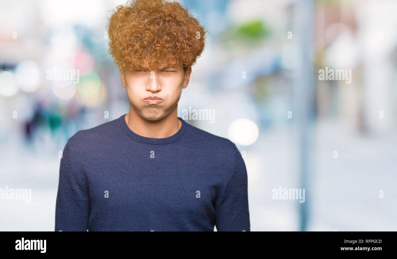 Young handsome man with afro hair puffing cheeks with funny face. Mouth ...
