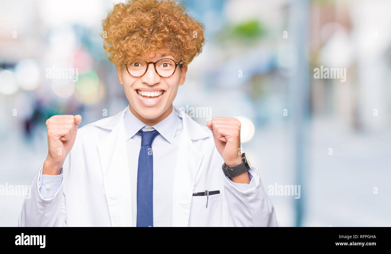 Young handsome scientist man wearing glasses celebrating surprised and ...