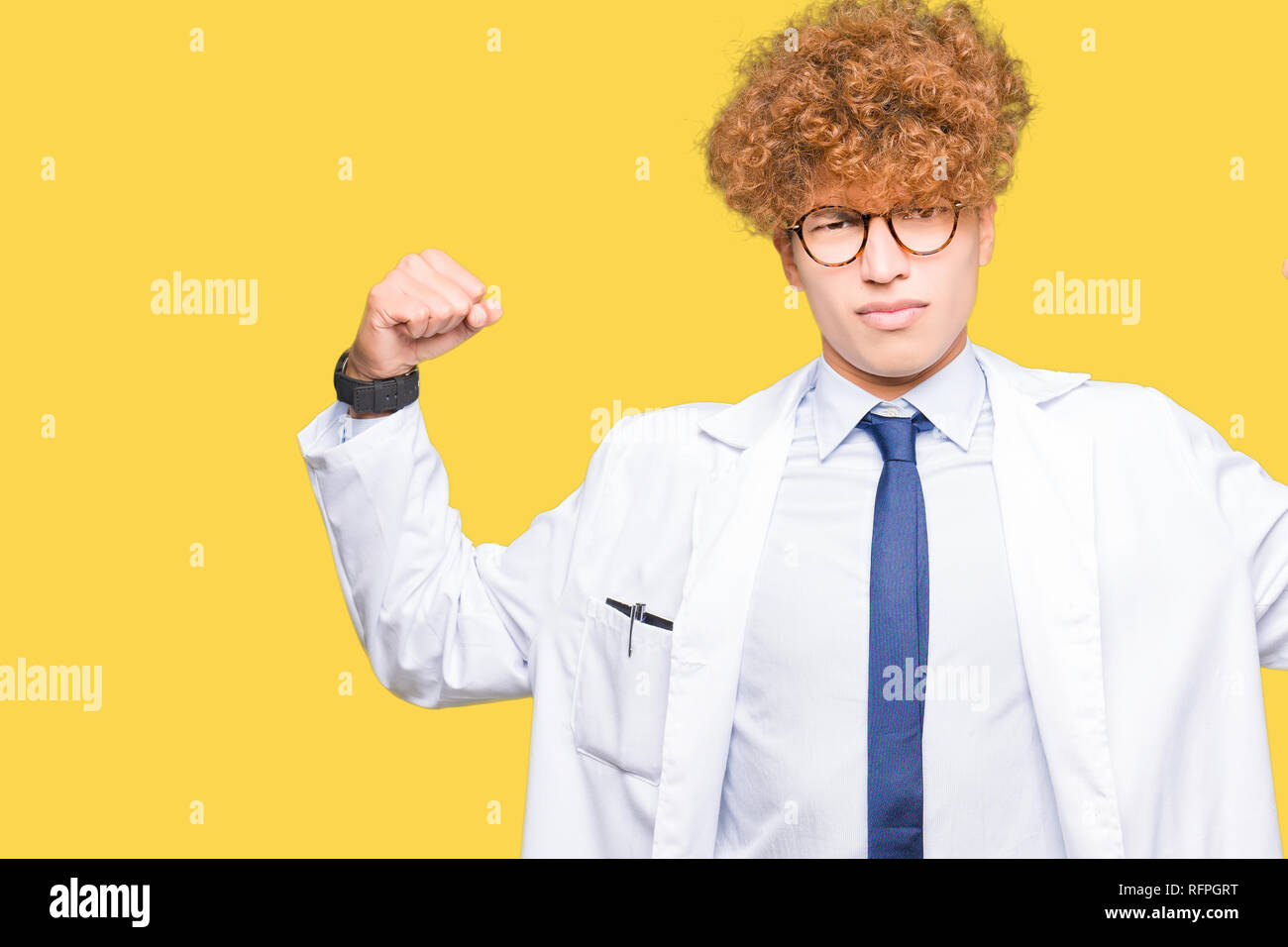 Young handsome scientist man wearing glasses showing arms muscles ...