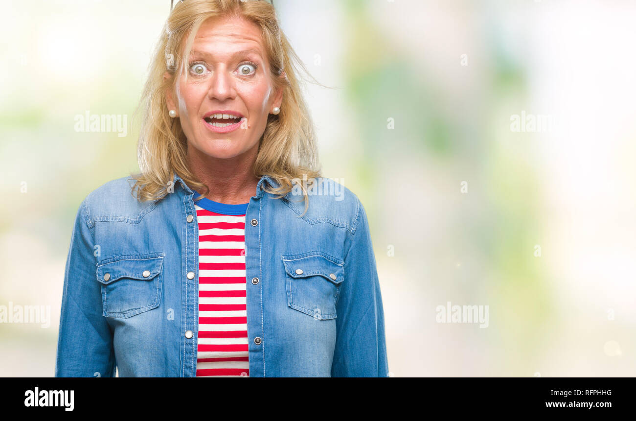 Middle age blonde woman over isolated background afraid and shocked with surprise expression ...
