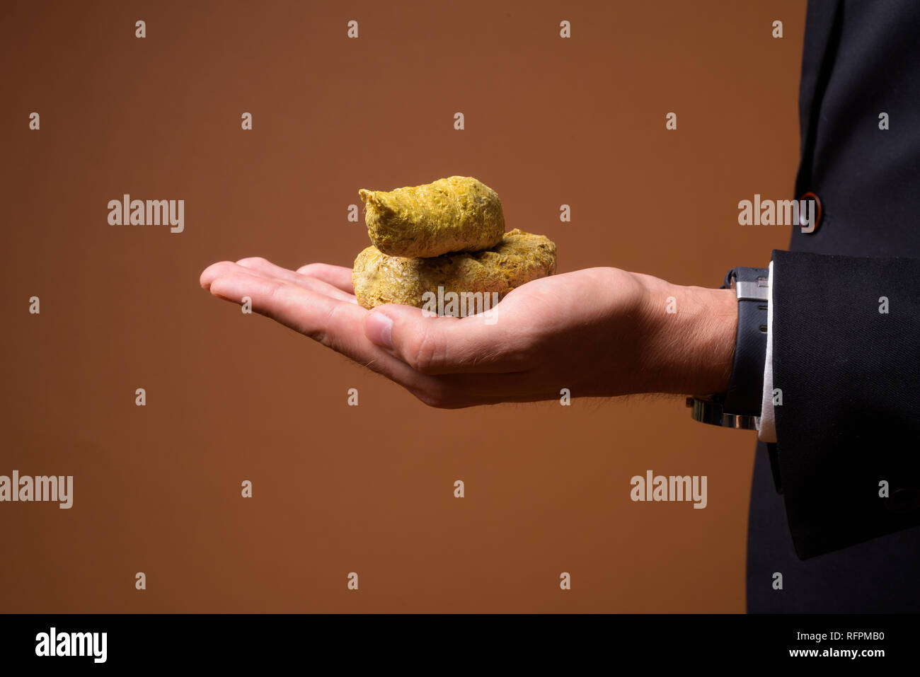 Hand of young businessman holding poop against brown background Stock ...