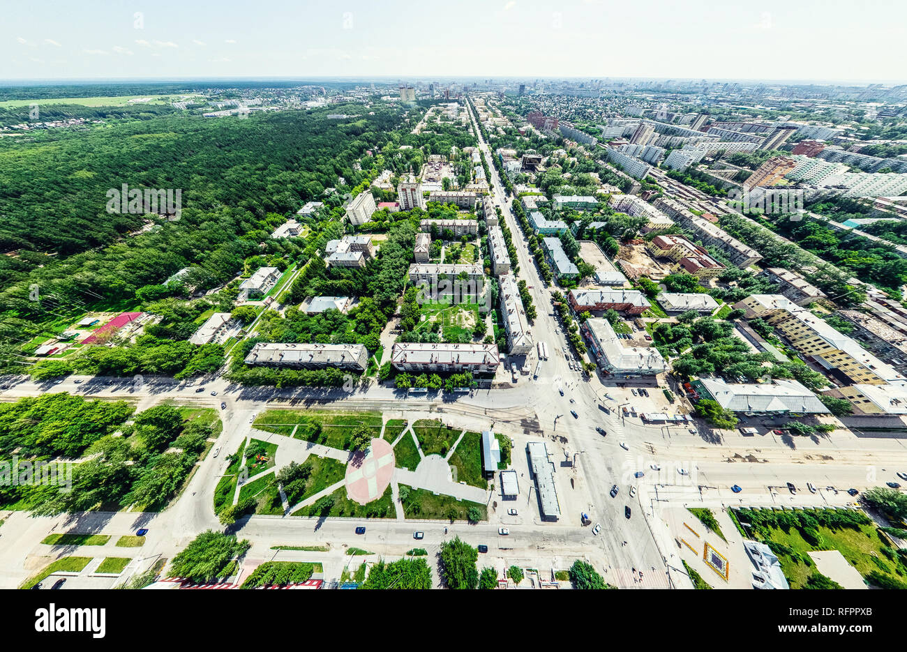 Aerial city view with crossroads and roads, houses, buildings, parks and parking lots. Sunny ...
