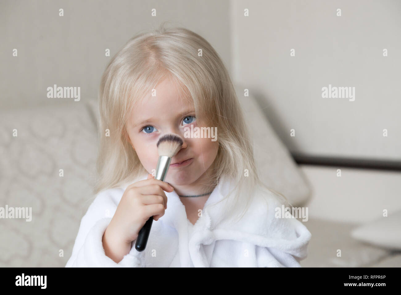 The girl powders her nose. A little girl with a brush applies make-up ...