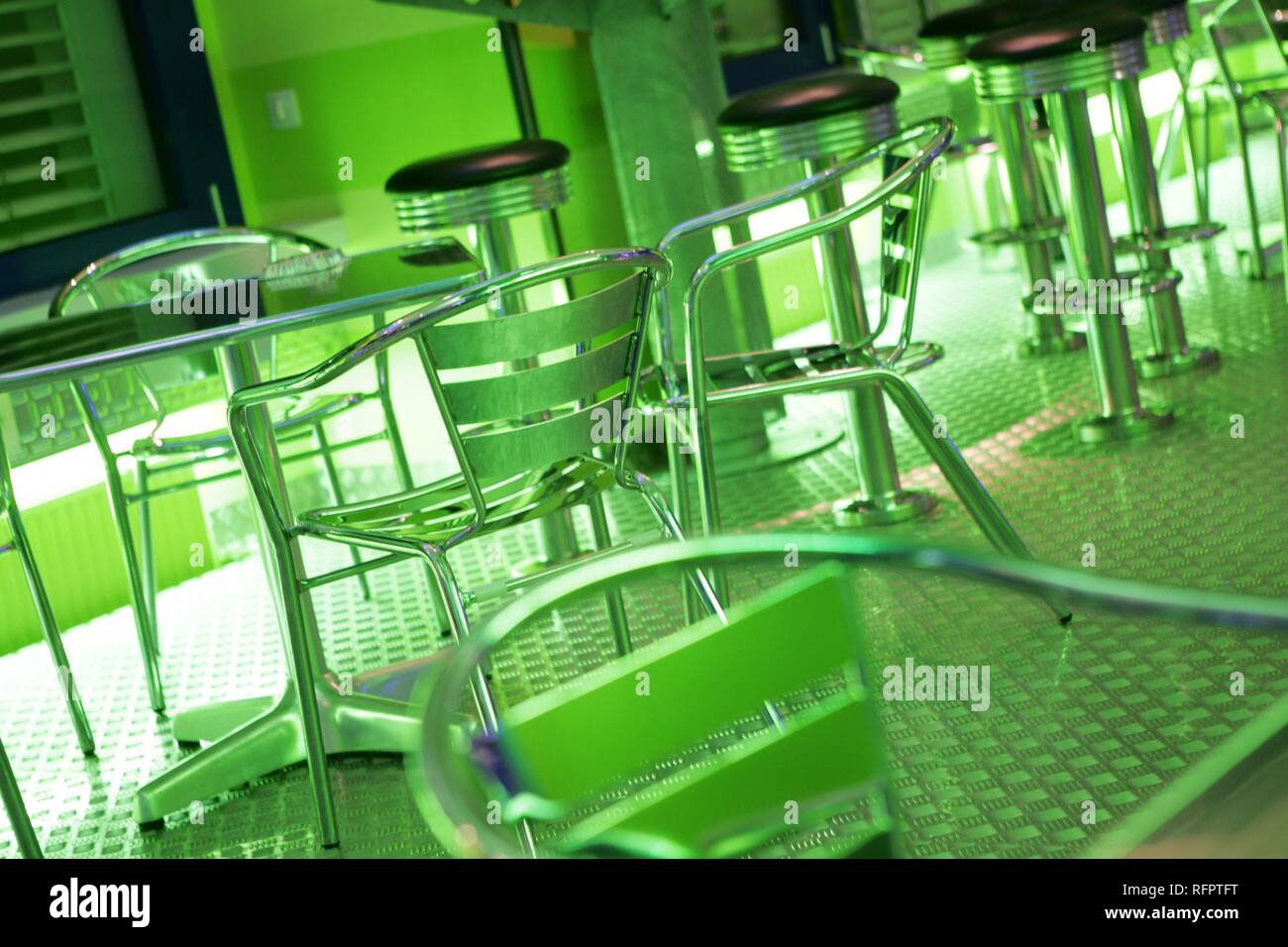 DEU, Germany: Chairs in metall design in a bar with green light Stock ...