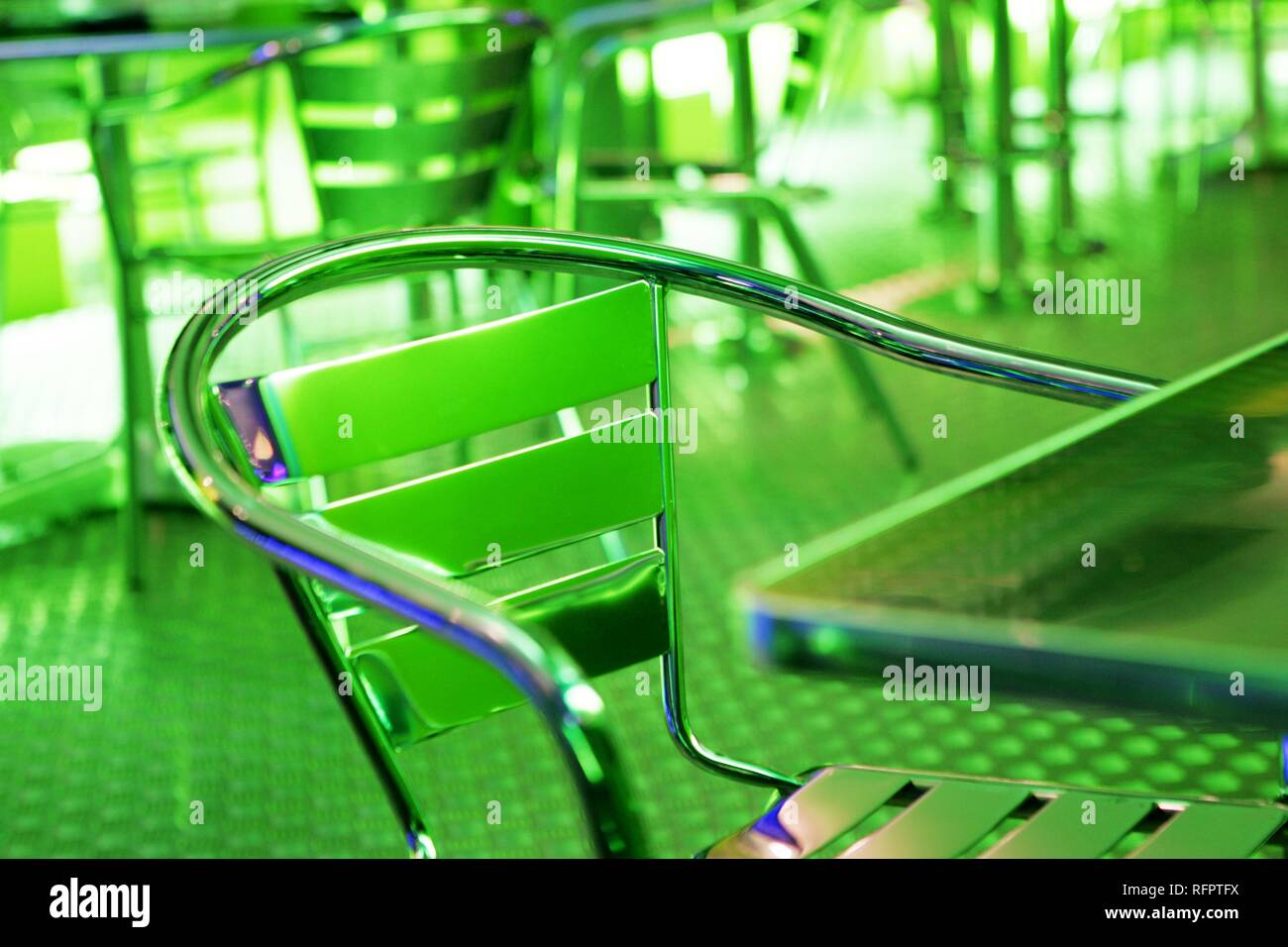 DEU, Germany: Chairs in metall design in a bar with green light Stock ...