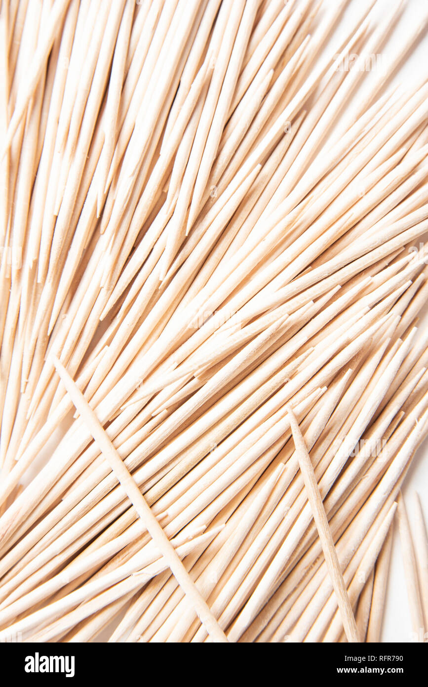 A bunch of unused round wooden toothpicks artfully scattered on a plain ...