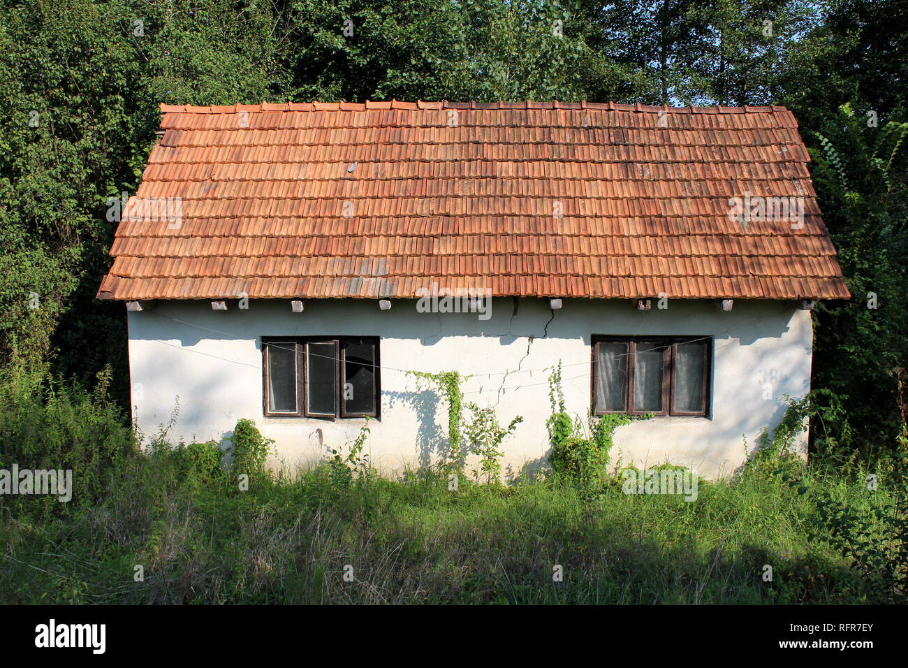 Abandoned small family house with cracked facade and broken windows ...
