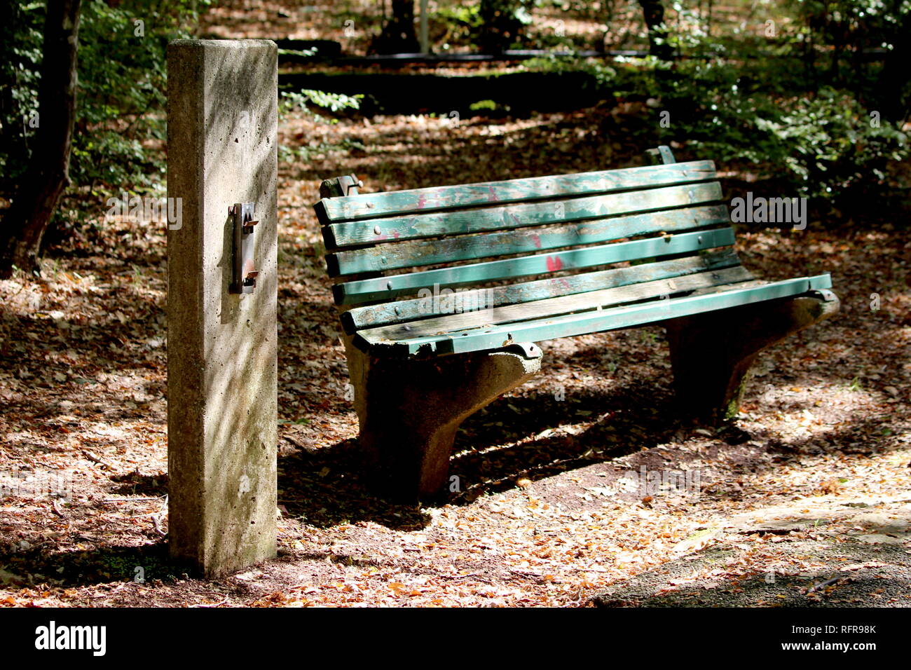 Heavily used old broken wooden public bench next to concrete pier with ...