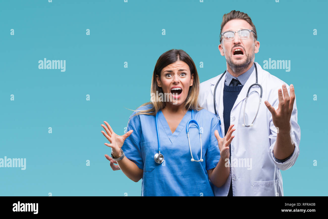 Young couple of doctor and surgeon over isolated background crazy and ...
