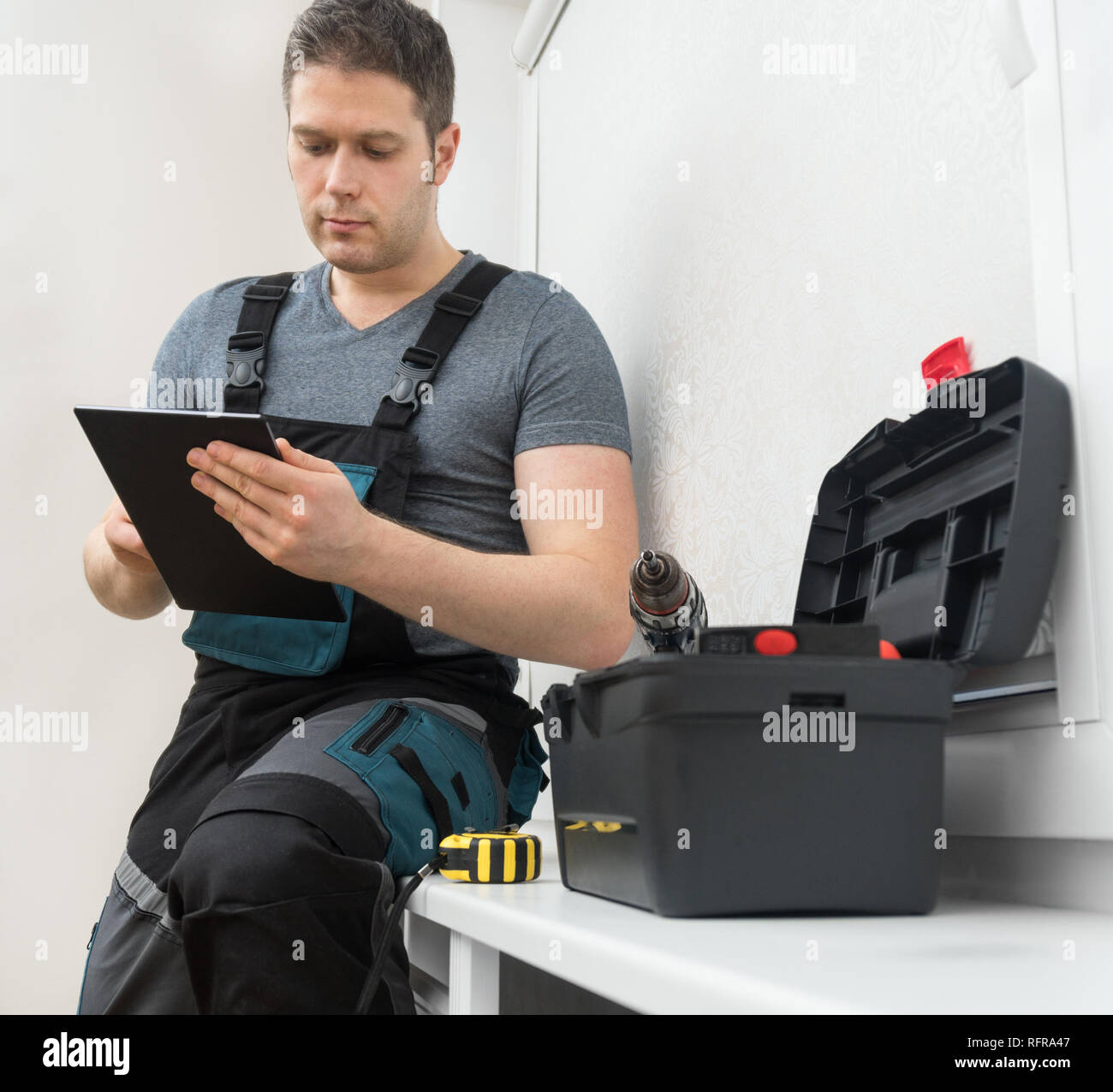 Professional contractor sitting at window with tablet pc Stock Photo ...