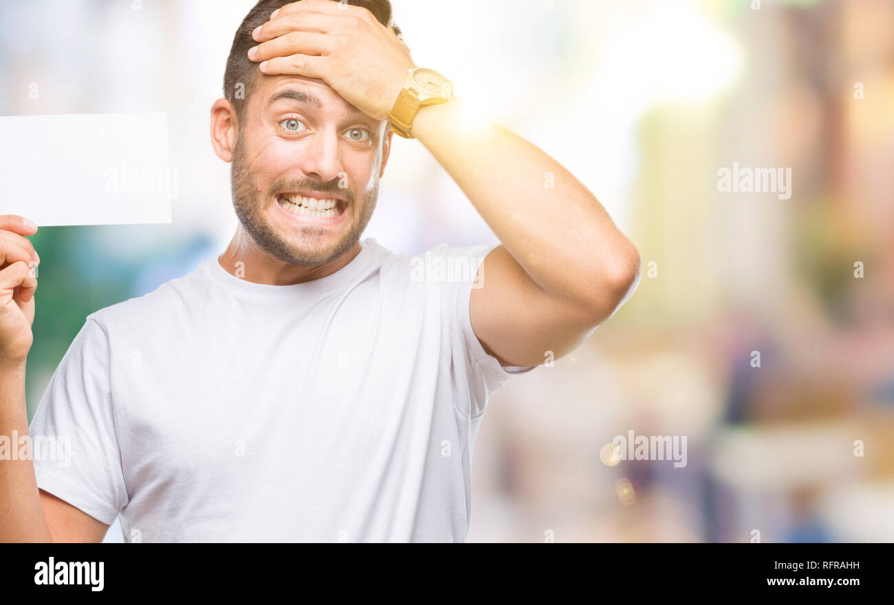 Young handsome man holding blank card over isolated background stressed ...