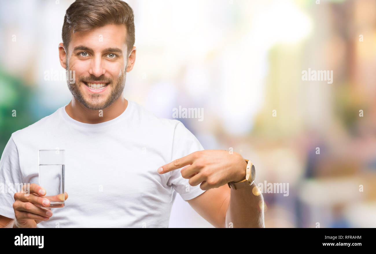 Young handsome man drinking glass of water over isolated background ...