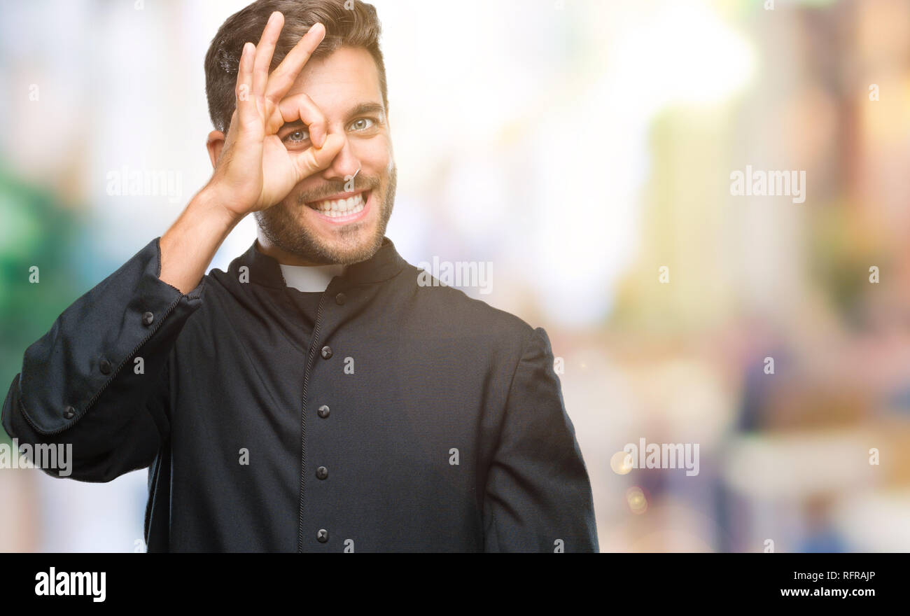 Young catholic christian priest man over isolated background doing ok ...