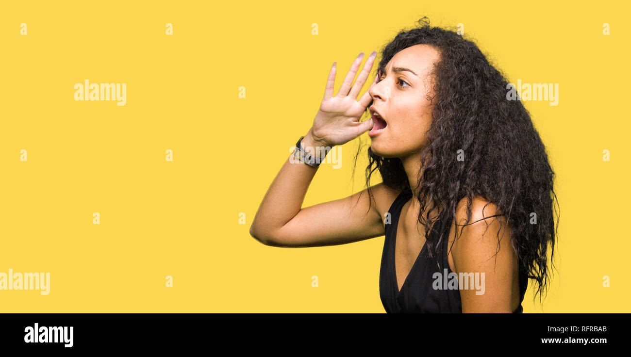 Young beautiful girl with curly hair wearing fashion skirt shouting and ...