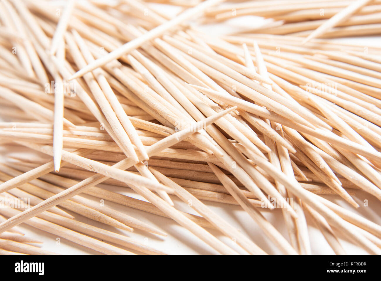 A bunch of unused round wooden toothpicks artfully scattered on a plain ...