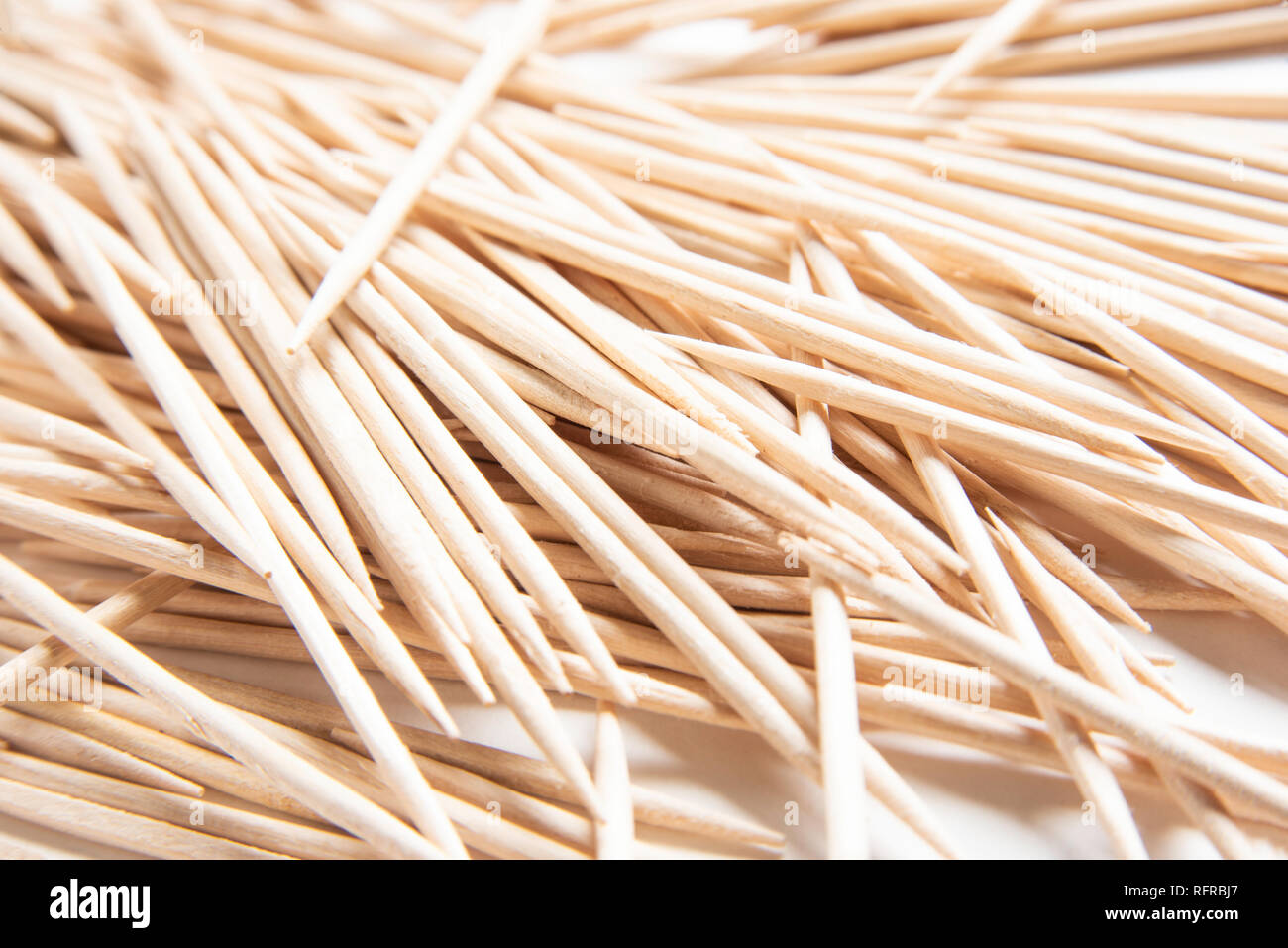 A bunch of unused round wooden toothpicks artfully scattered on a plain ...
