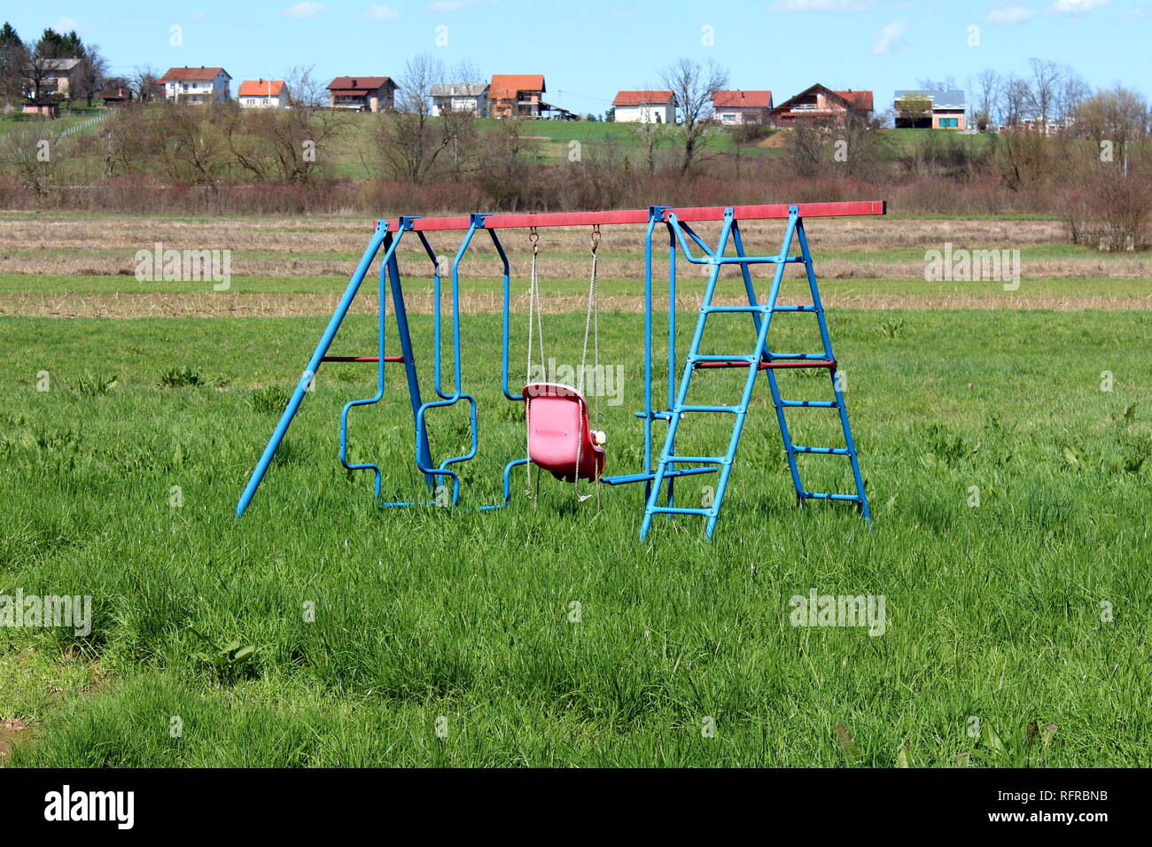 Outdoor public playground equipment metal swing with faded blue frame ...