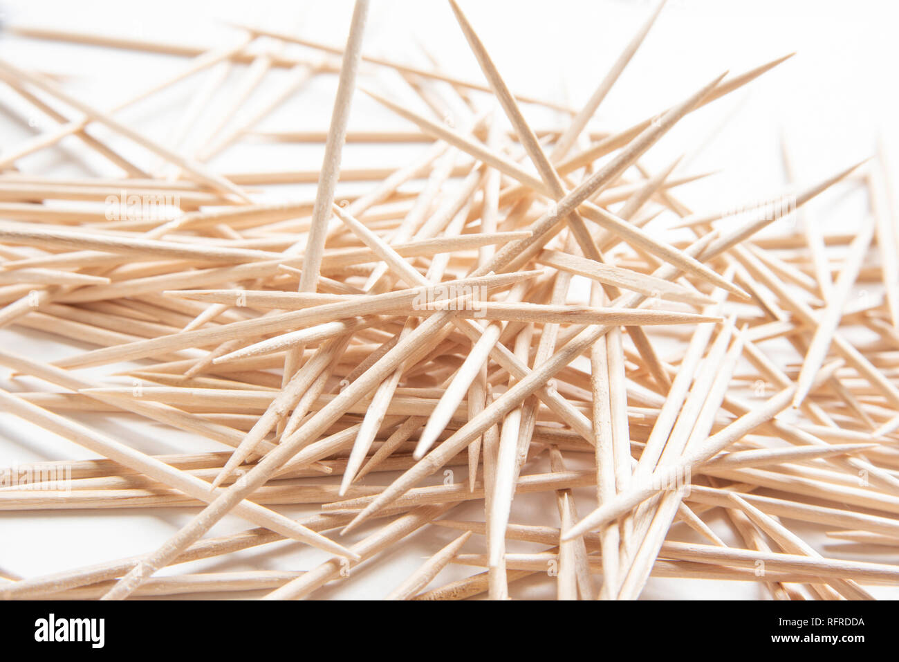A bunch of unused round wooden toothpicks artfully scattered on a plain ...