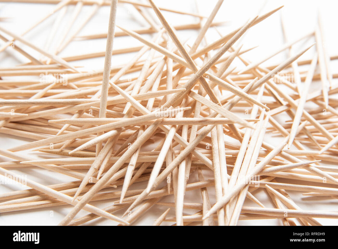 A bunch of unused round wooden toothpicks artfully scattered on a plain ...
