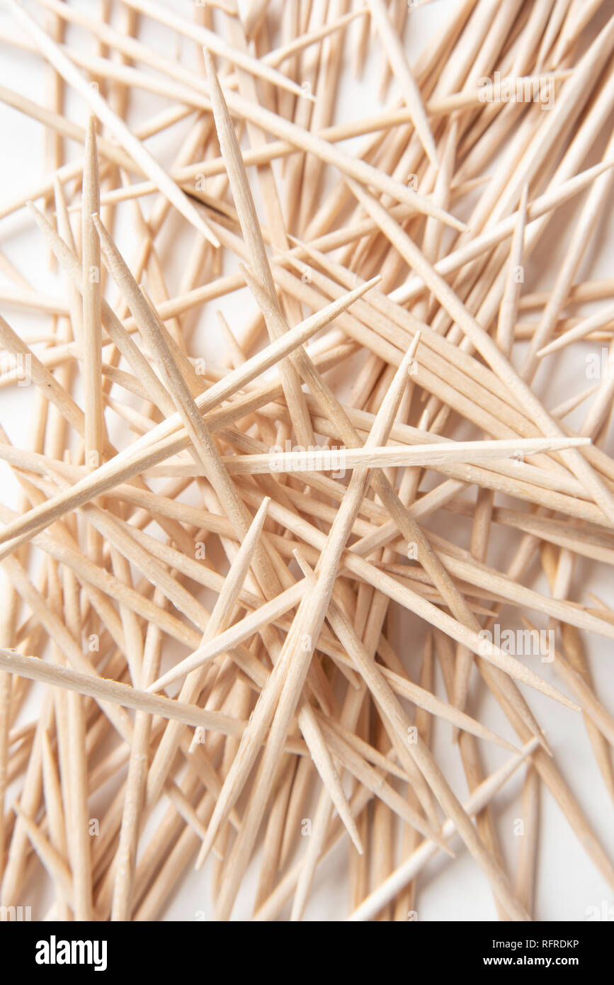 A bunch of unused round wooden toothpicks artfully scattered on a plain ...