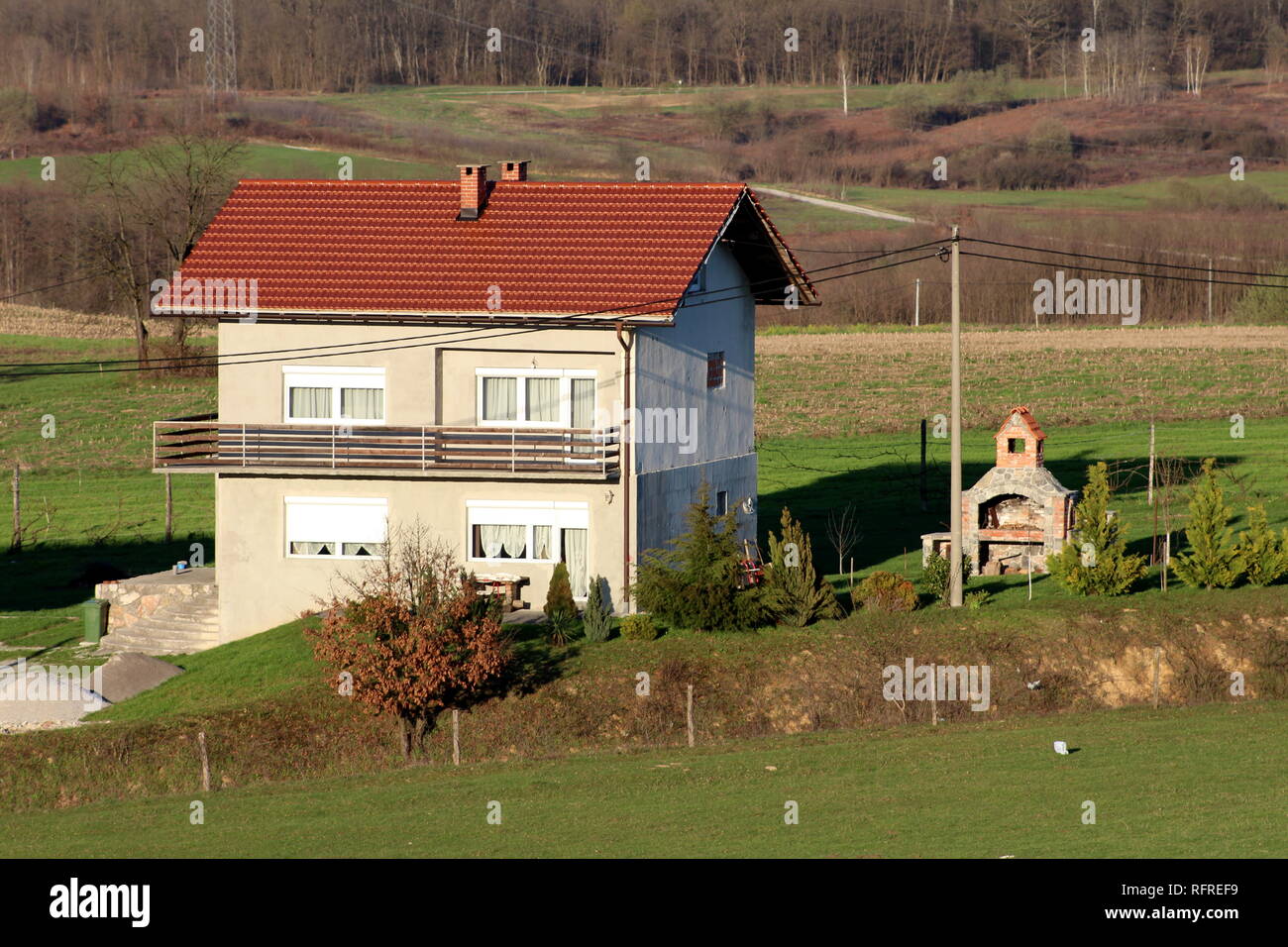 Traditional stone barbecue next to suburban family house with long ...