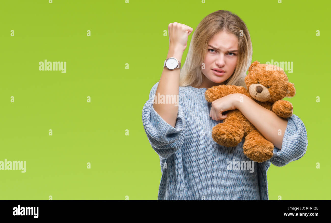 Young caucasian woman holding cute teddy bear over isolated background ...
