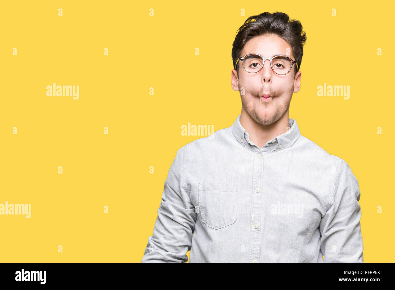 Young handsome man wearing glasses over isolated background making fish ...