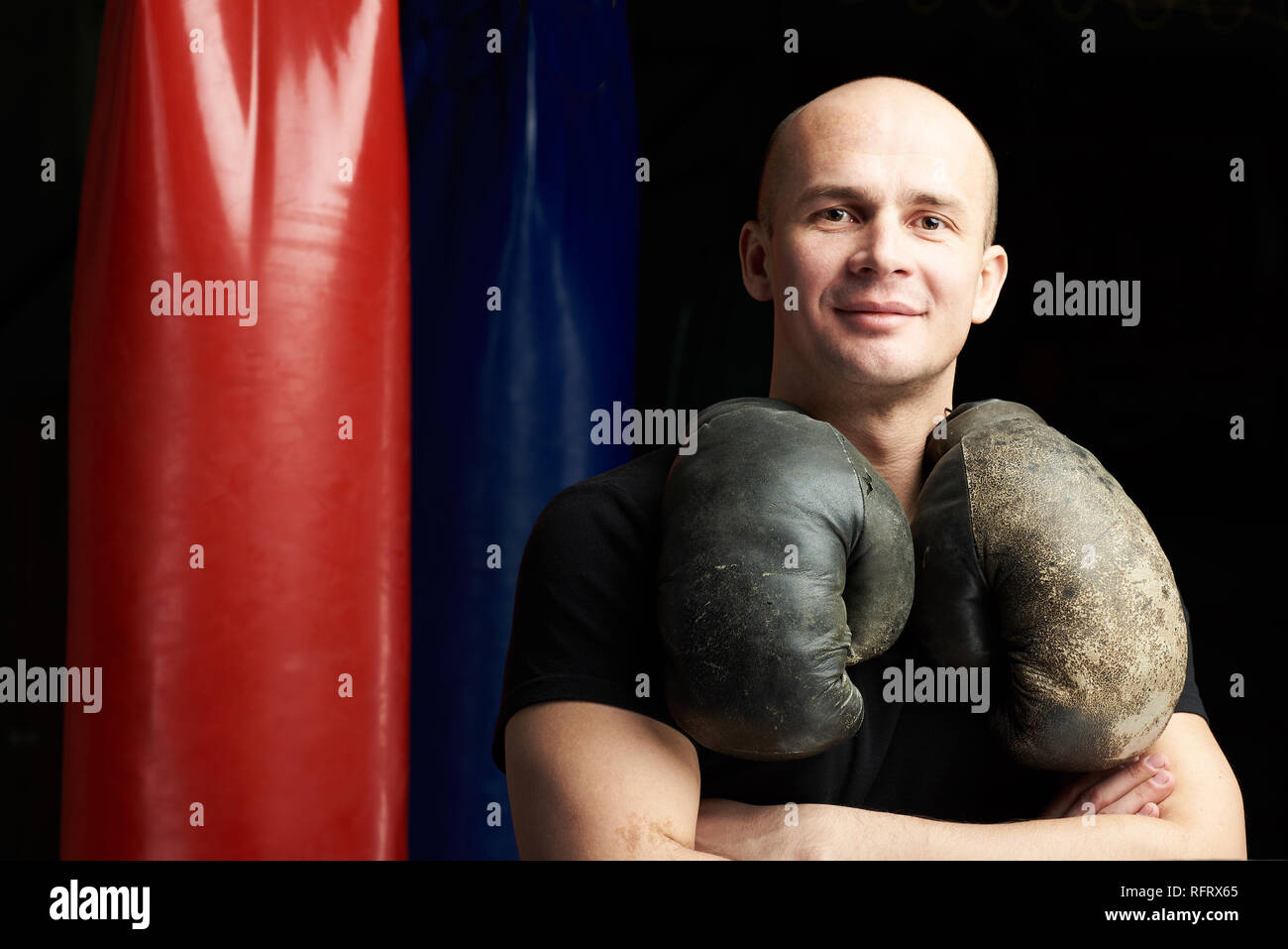 Close-up portrait of boxing man with grungy gloves hanging on neck ...