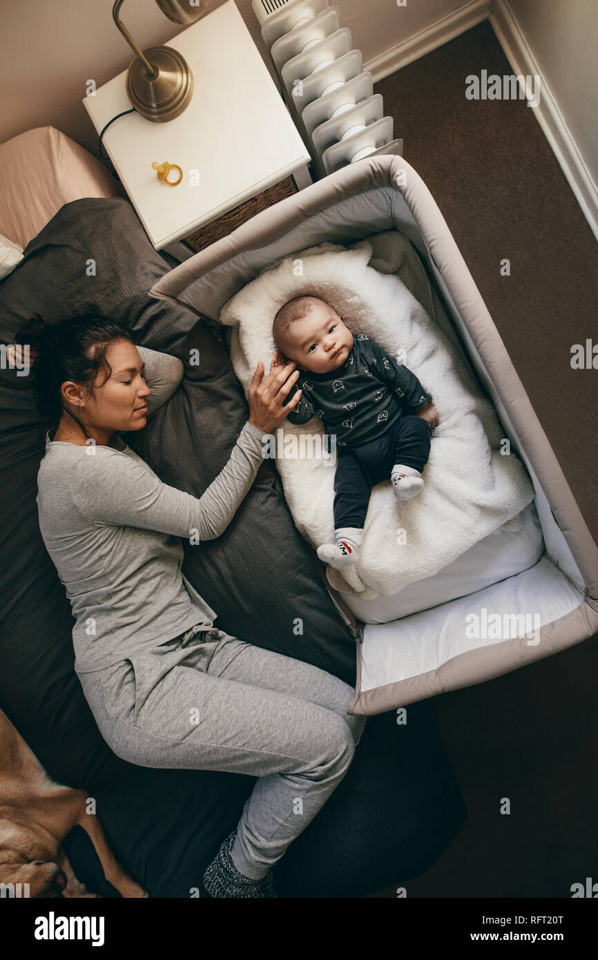 Mother and child sleeping on bed at home. Woman sleeping on bed holding ...