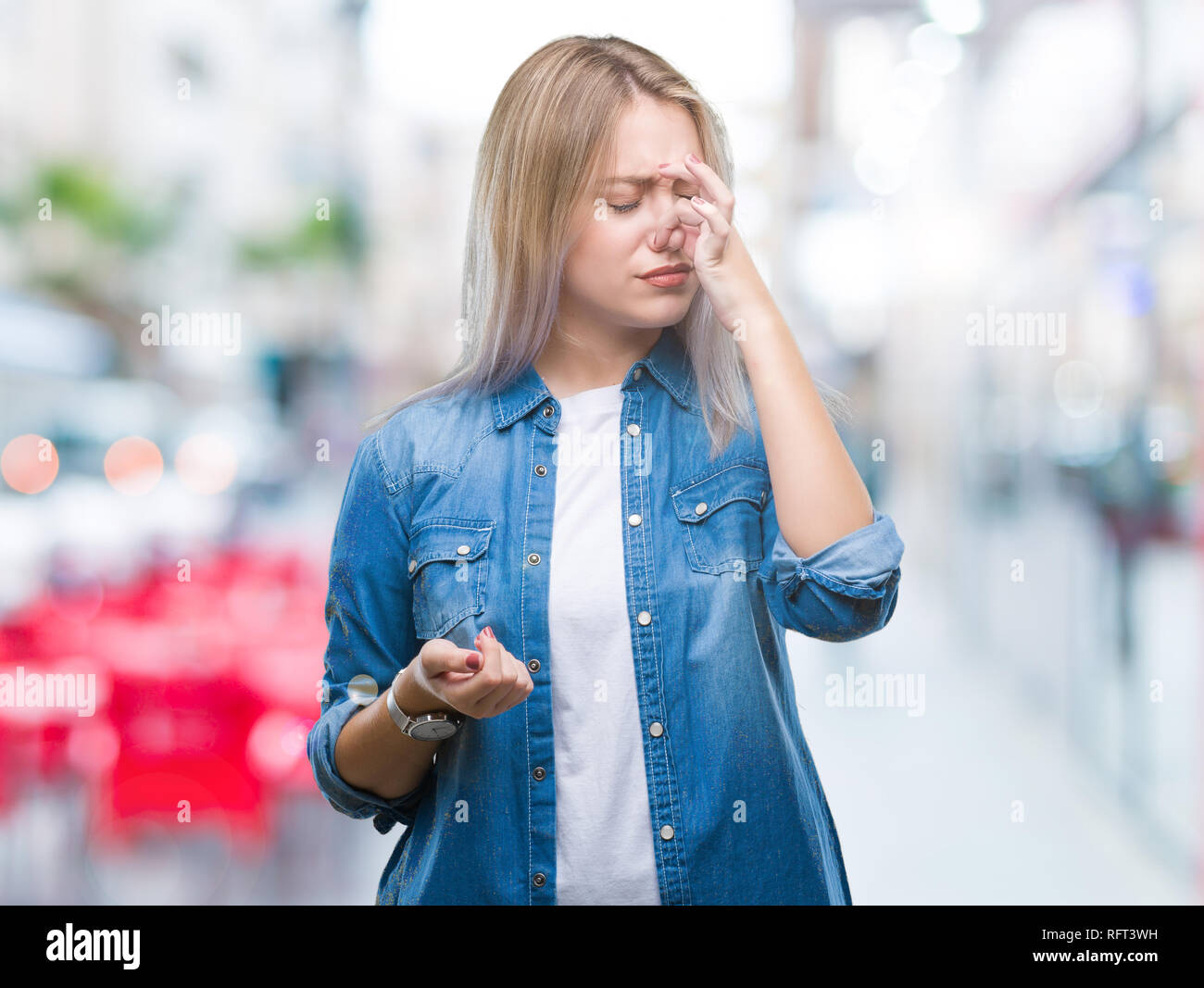 Young blonde woman over isolated background smelling something stinky ...