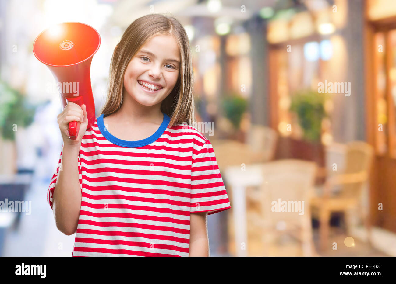 Young beautiful girl yelling through megaphone over isolated background ...