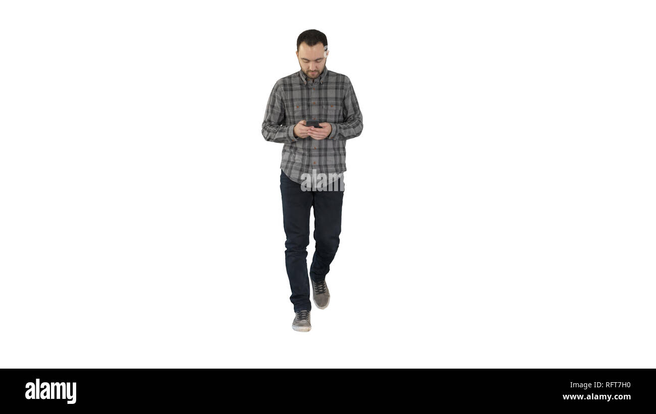 Full length portrait. Young man walking and using a phone, messaging on ...