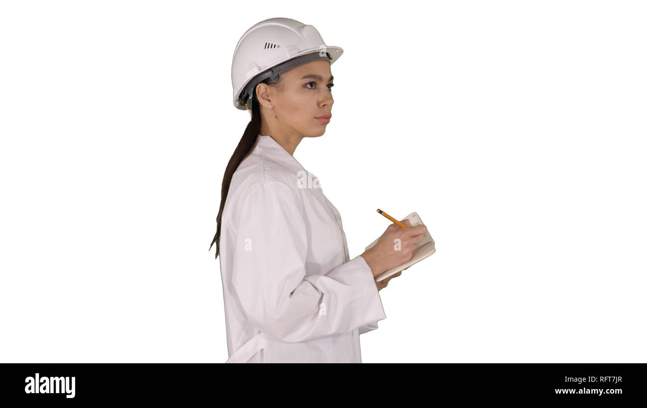 Medium shot. Side view. Woman engineer with helmet is holding pen and ...