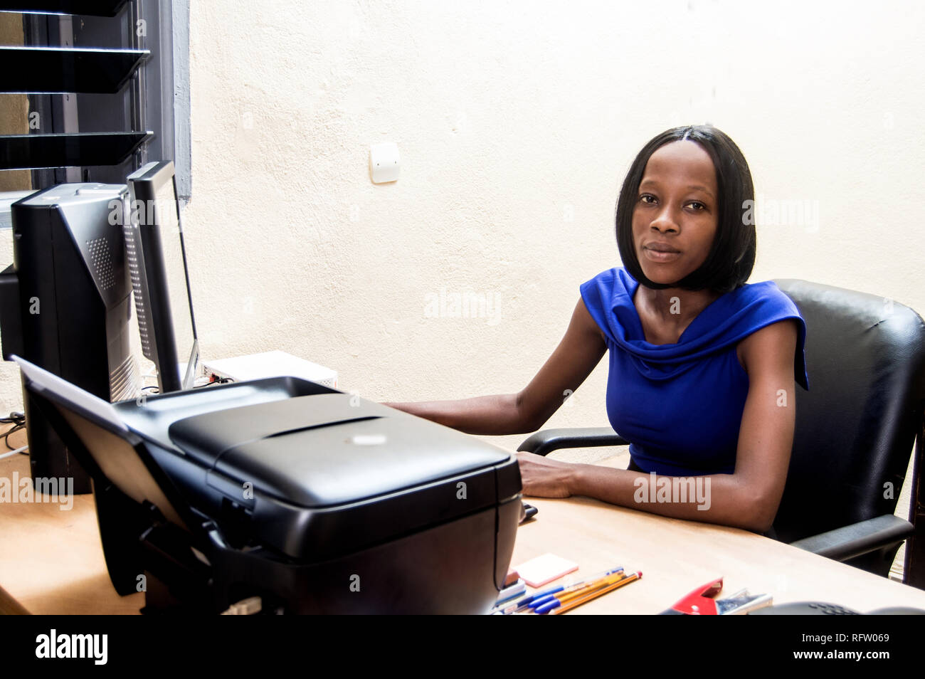 Young secretary typing a text while watching the camera Stock Photo - Alamy