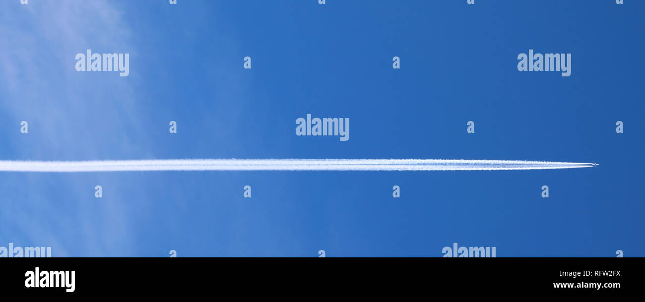 Engine exhaust white contrails forming behind an airliner flying high ...
