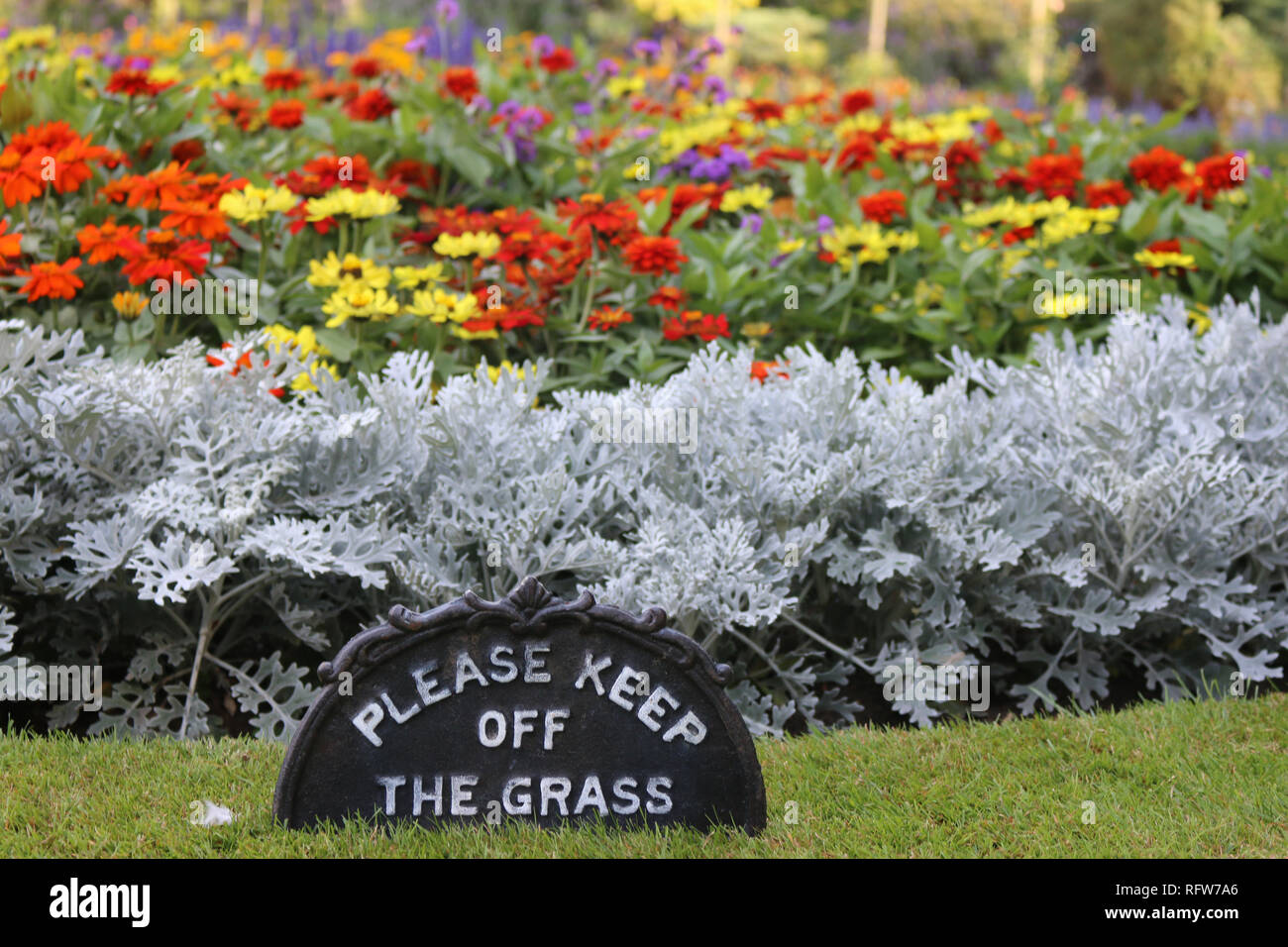 Please keep off the grass sign on a neatly edged grass lawn in front of ...