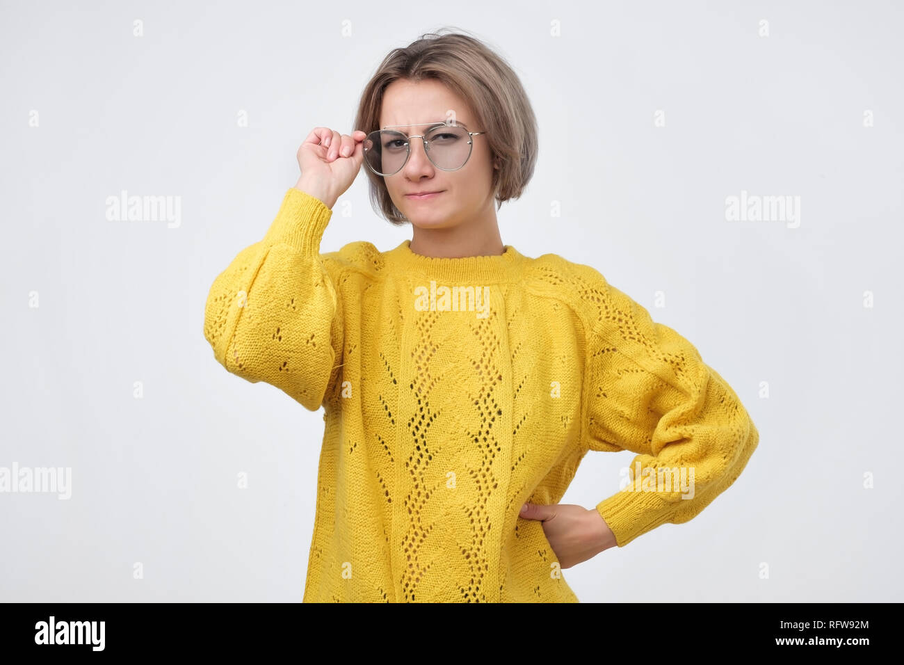 Girl in yellow sweater cannot read sign putting on glasses squinting ...
