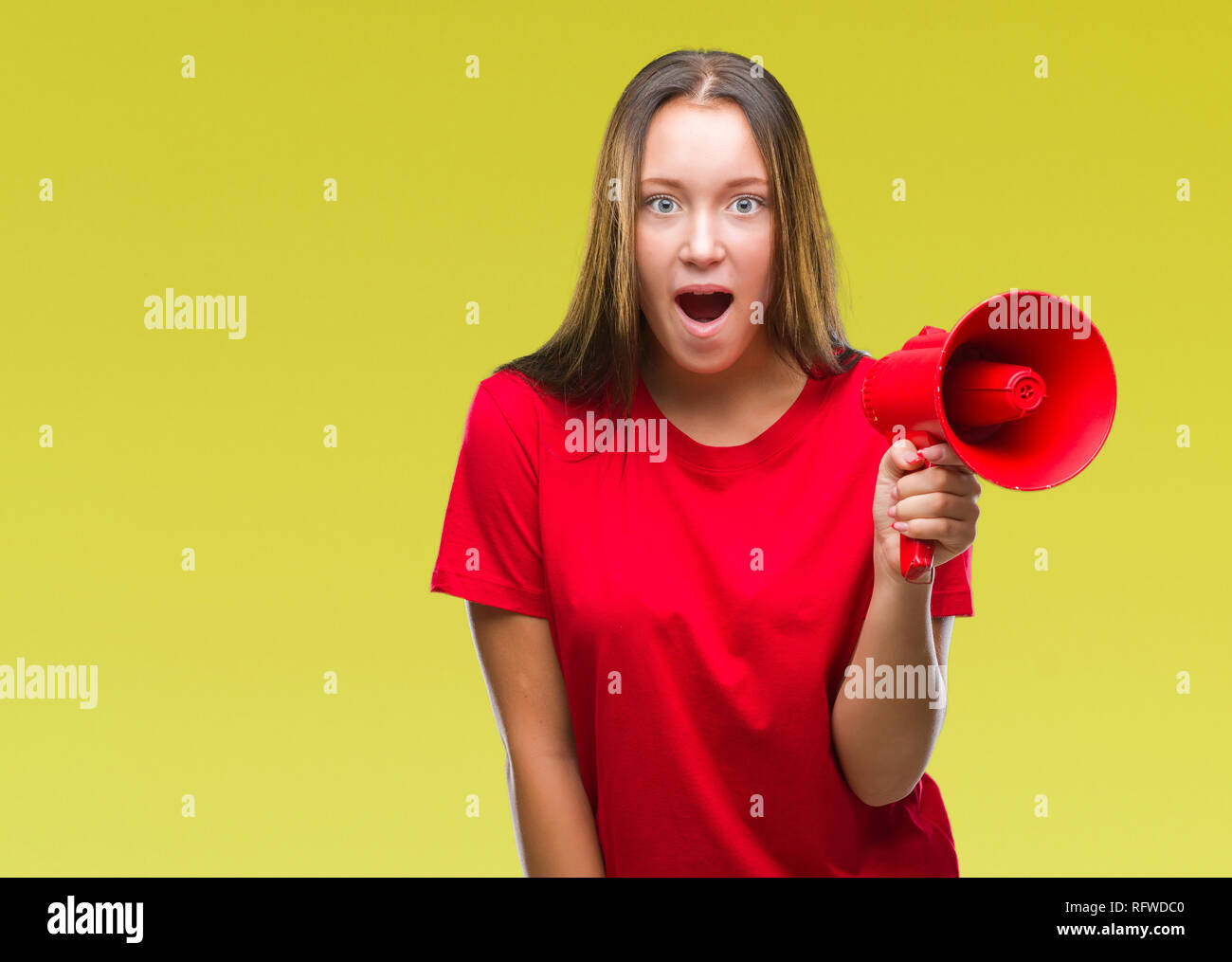 Young caucasian woman yelling through megaphone over isolated ...